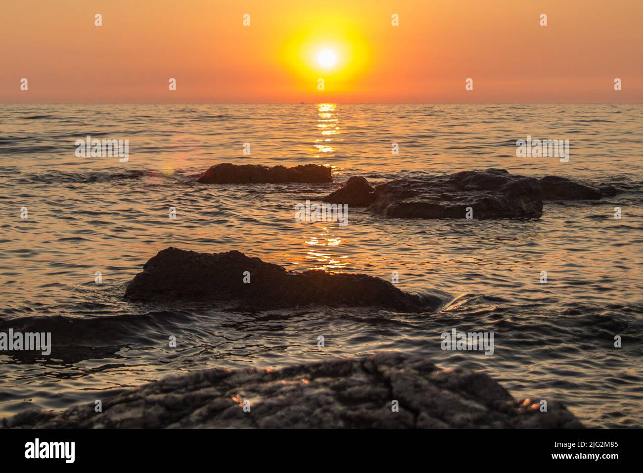 Sunset over the sea among the rocks Stock Photo - Alamy