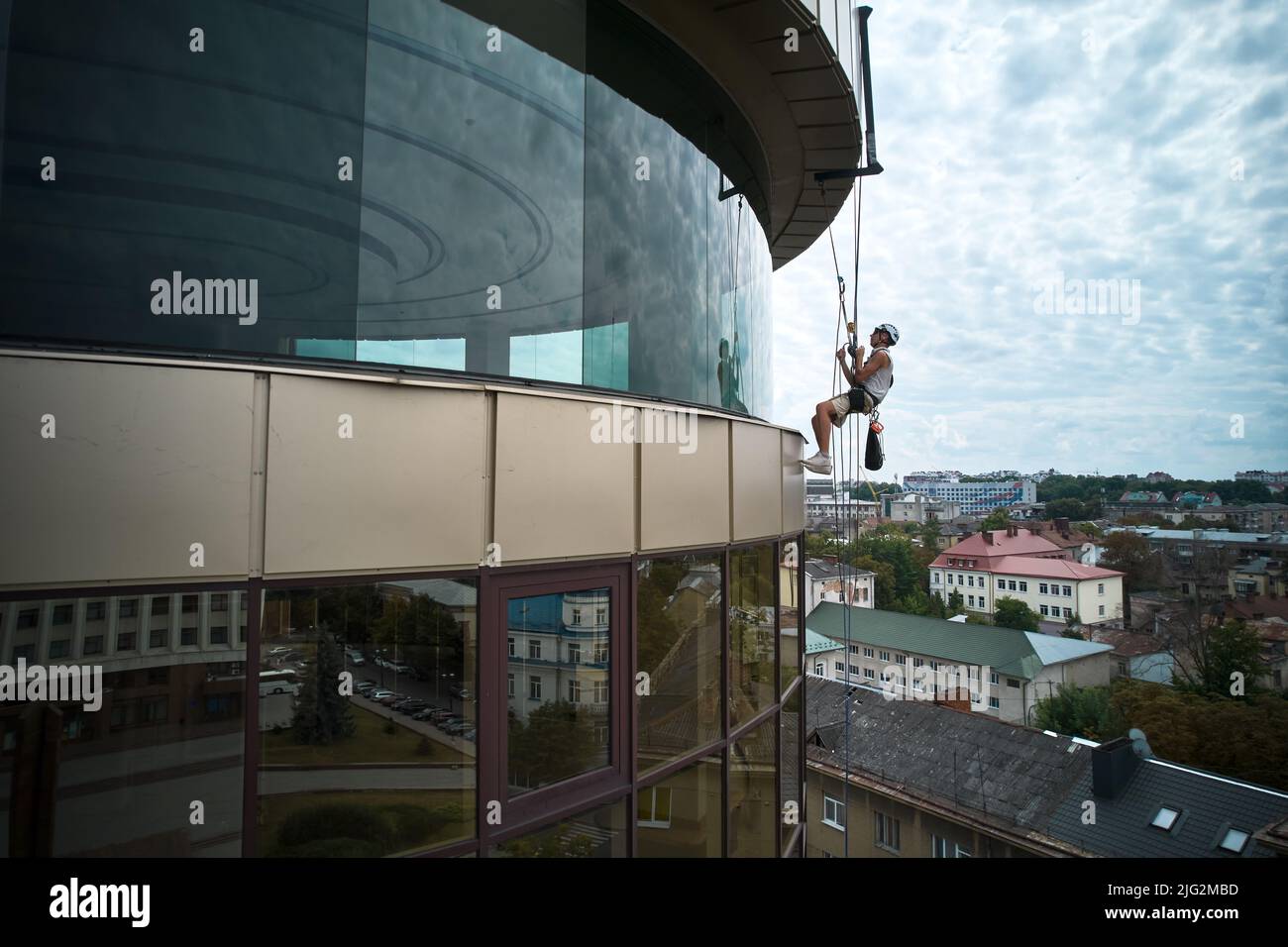 Industrial mountaineering worker cleaning glass window of high-rise ...