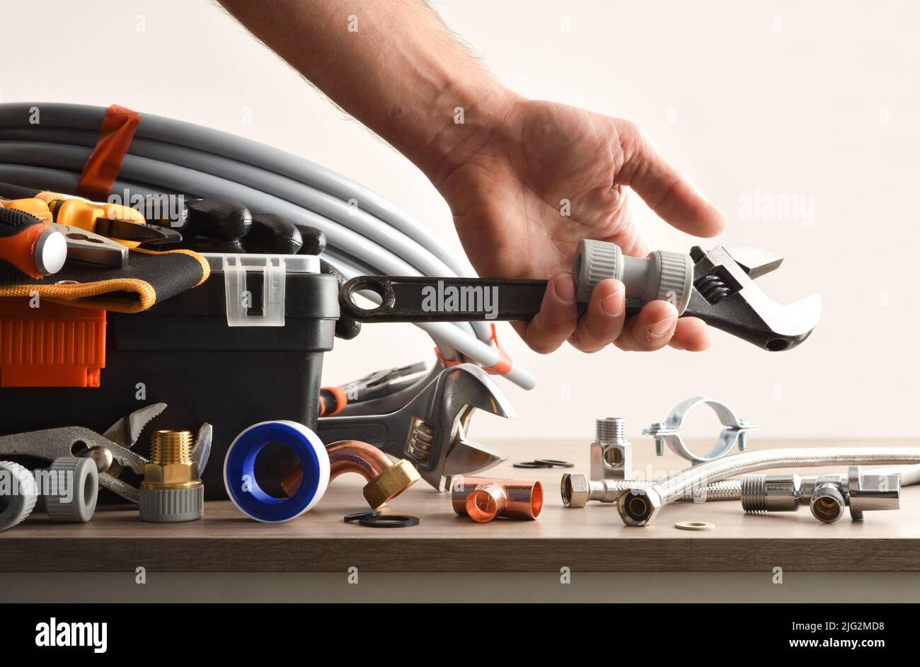 Plumber toolbox with material on wooden table and hand picking ...