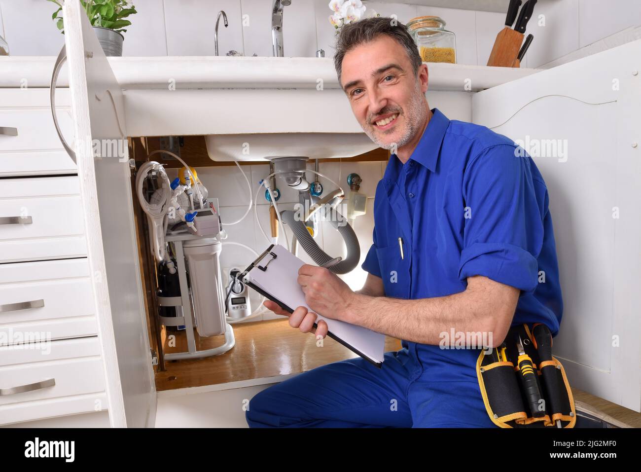 Plumbing technician checking water installation under the sink of a ...