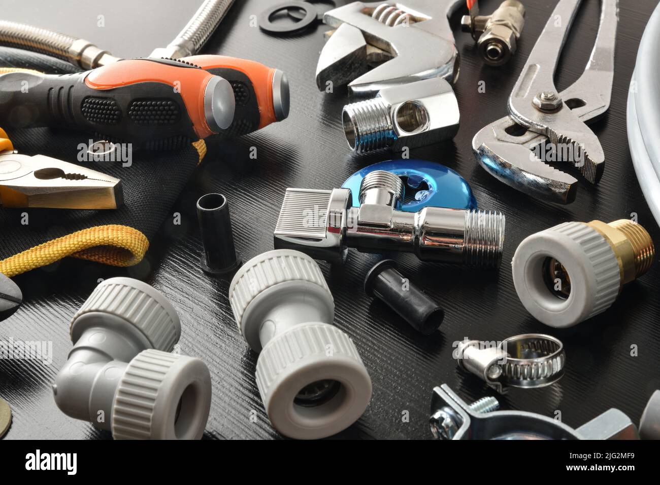 Detail of group of plumbing materials and tools on black table ...
