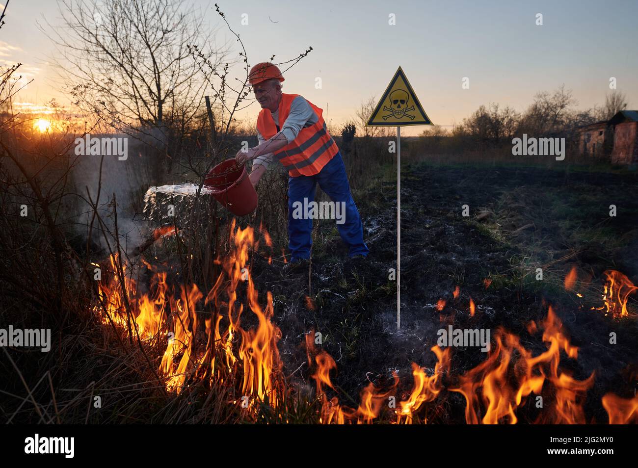 Fireman ecologist fighting wildfire in field with evening sky on ...