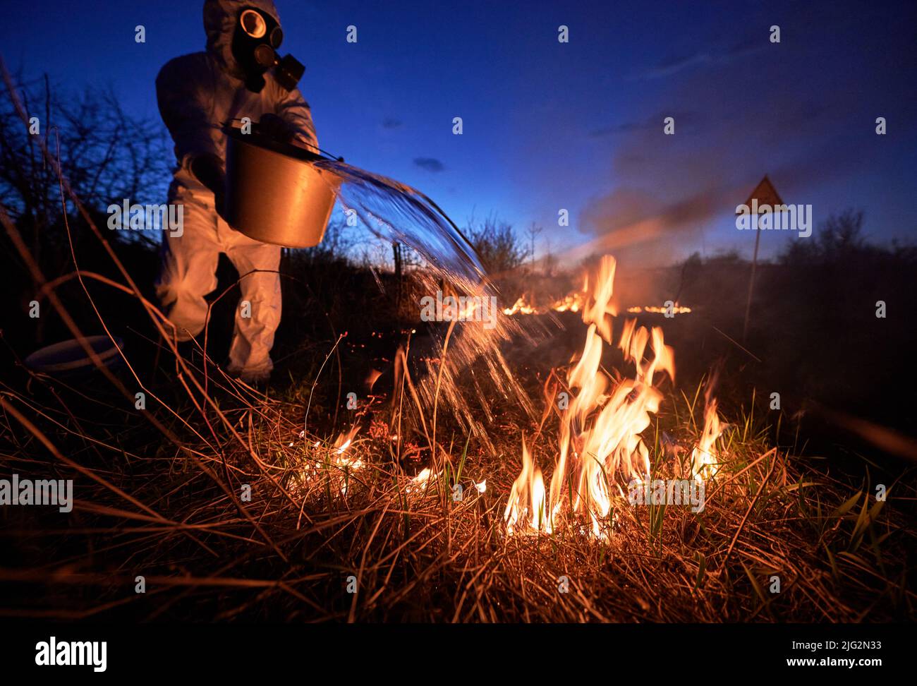Research scientist extinguishing fire in field with blue night sky on ...