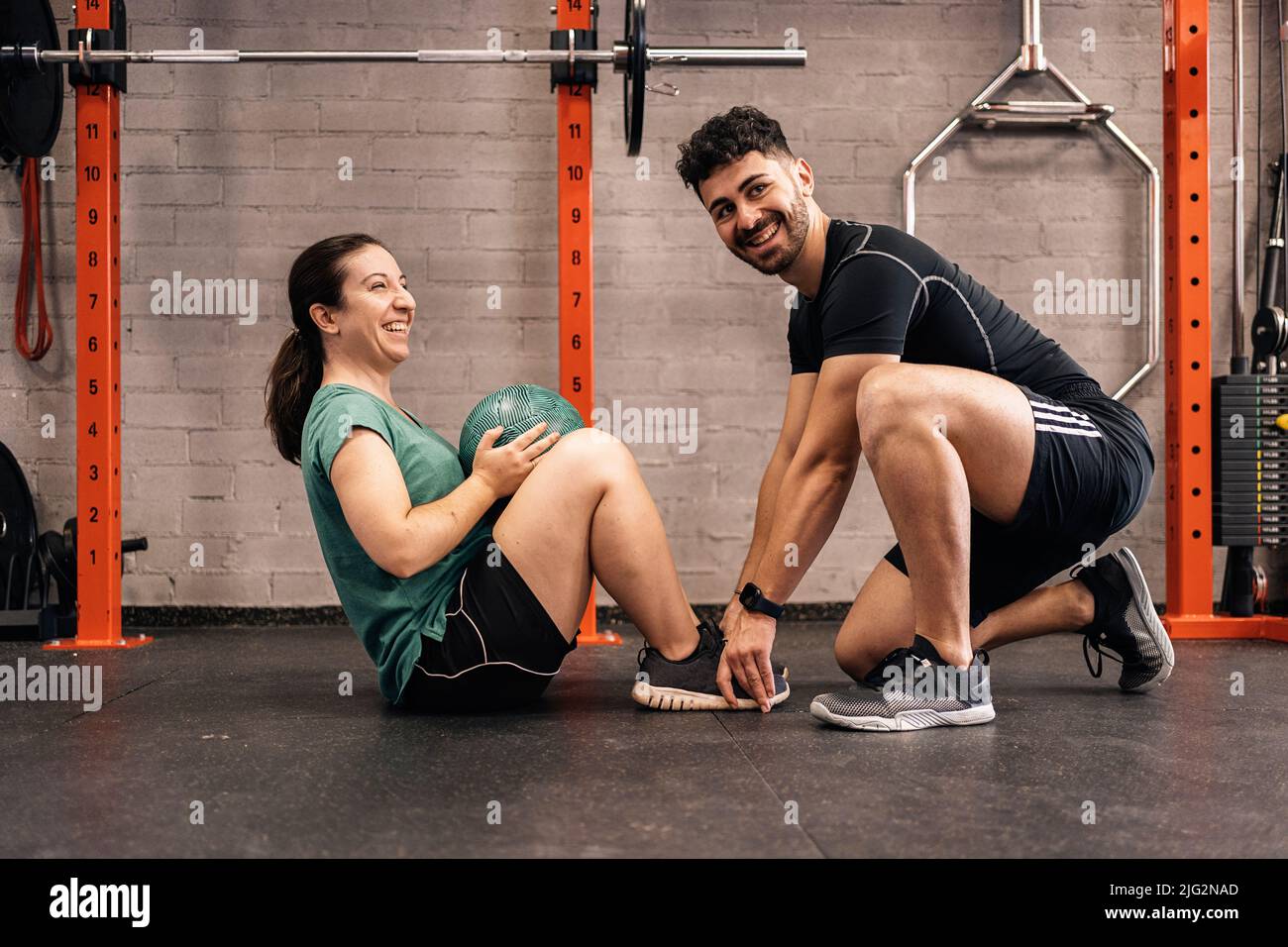 Personal trainer with a first-time trainee correcting habits in the ...