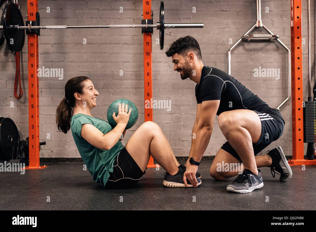 Personal trainer with a first-time trainee correcting habits in the ...