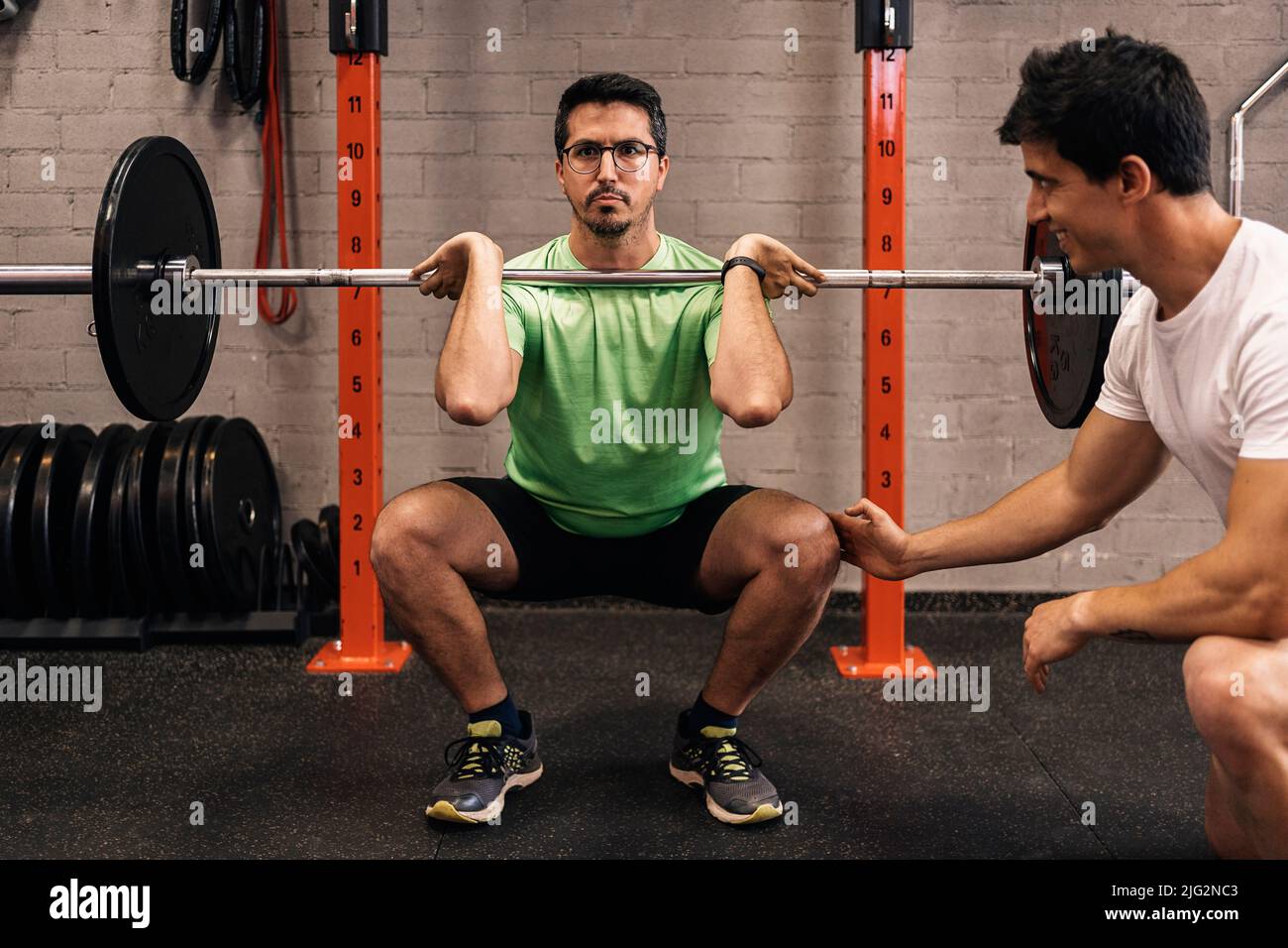 Personal trainer with a first-time trainee correcting habits in the ...