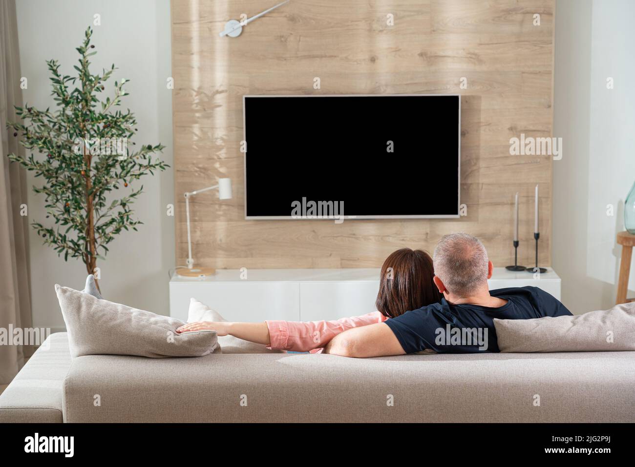adult couple in modern living room in front of tv Stock Photo - Alamy