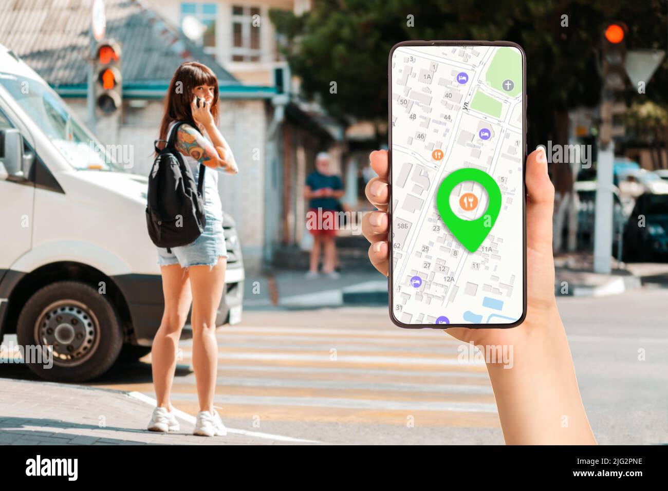 A hand holds a smartphone with an online map app and a marked ...