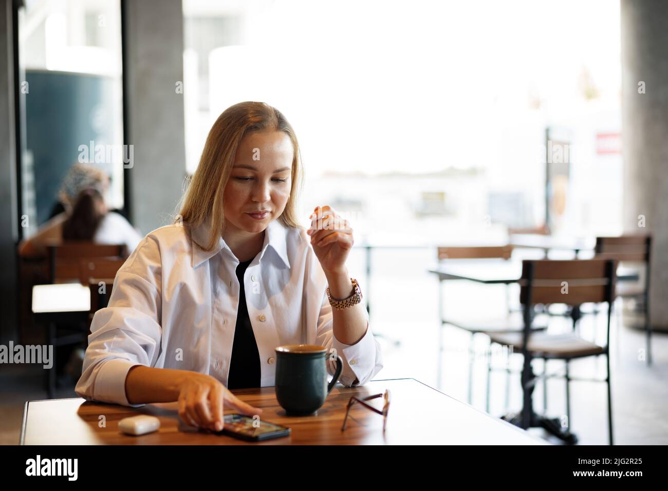 Woman typing text message on smart phone while sitting in a cafe Stock ...