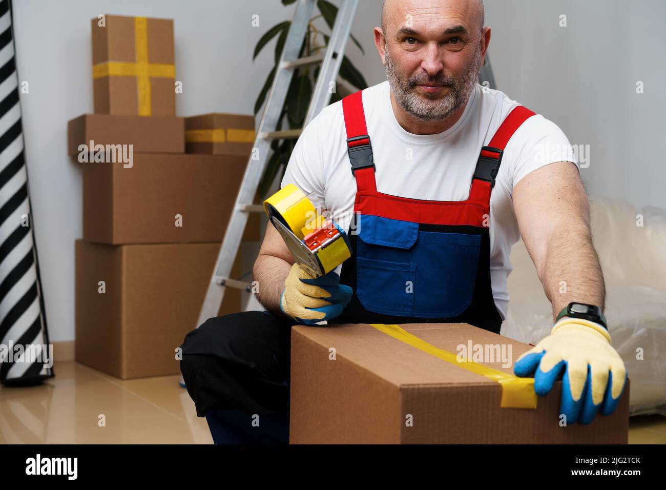 Man mover in uniform packing boxes with scotch tape Stock Photo - Alamy
