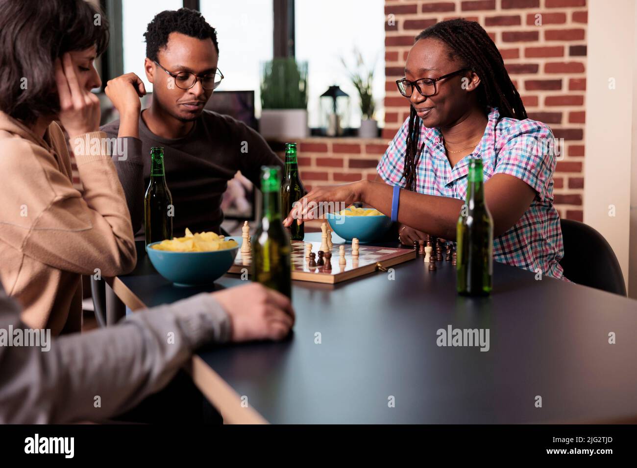 Smart people sitting at table in living room while playing chess ...