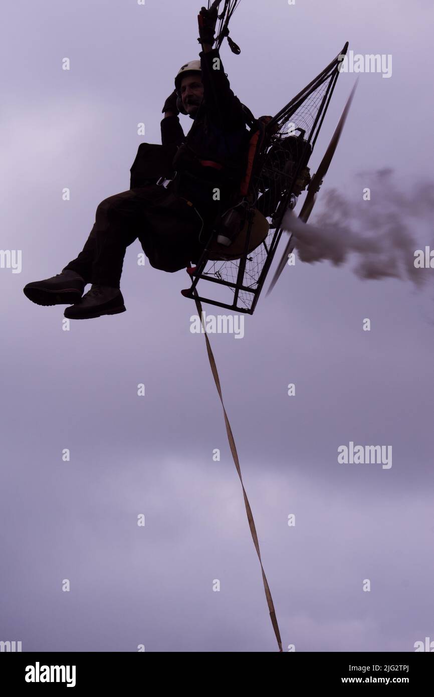 Parachute pilot flying with engine at a cloudy weather with smoke at ...