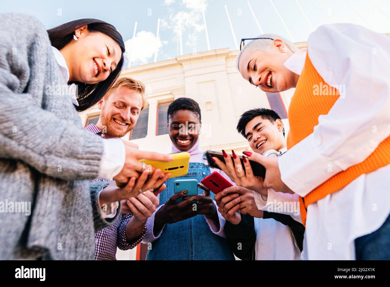 Five cherful friends using his cellphone and having fun together. Low ...