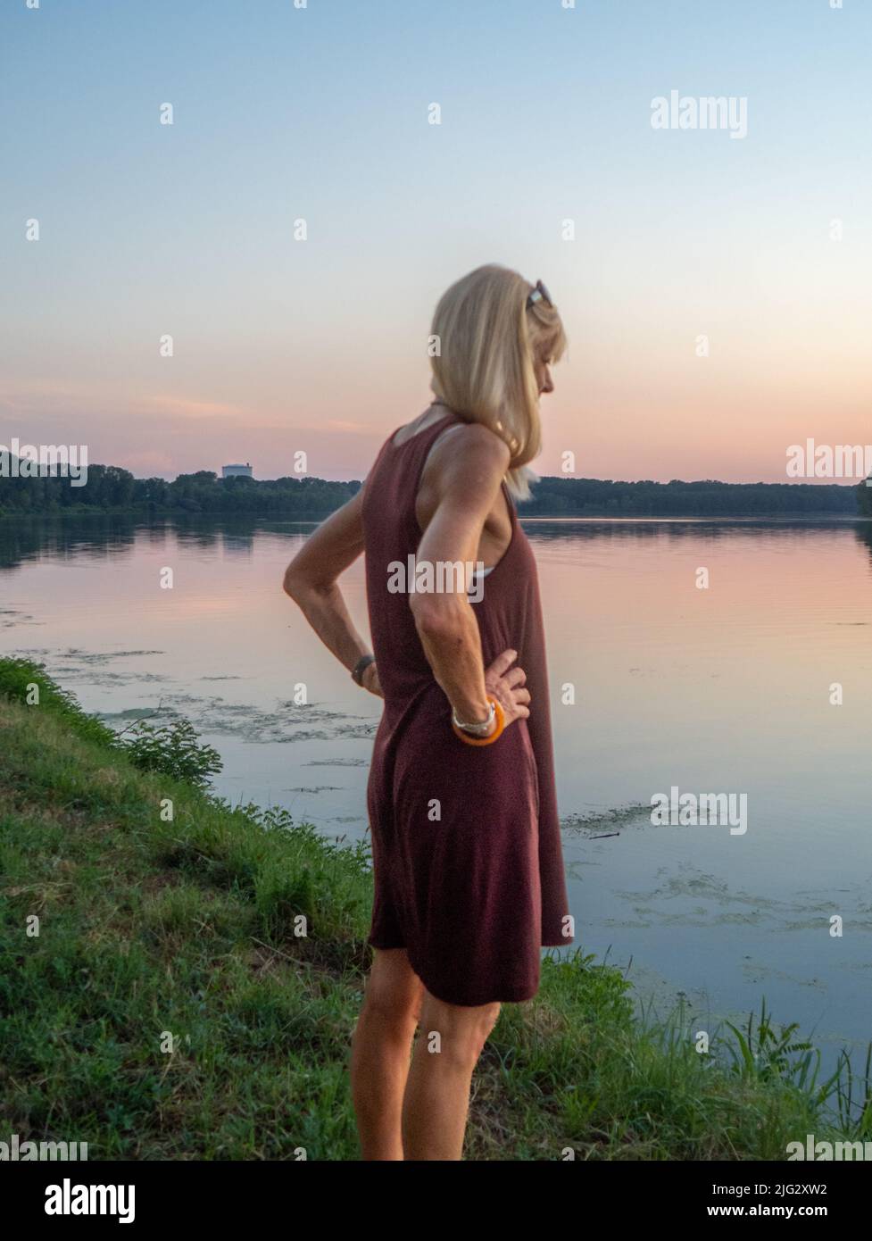 Beautiful woman enjoys holidays at sunset near river Stock Photo - Alamy