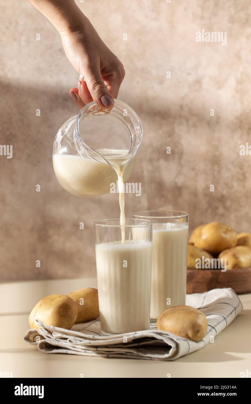 Potato milk is poured into a glass from a jug. Lactose-free milk Stock ...