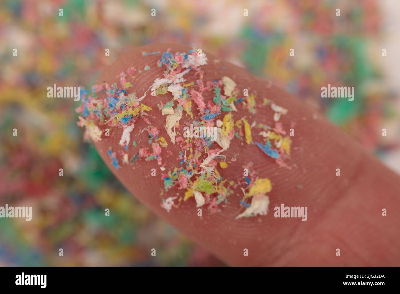 Colorful micro plastic particles on a finger, close-up. Macro ...