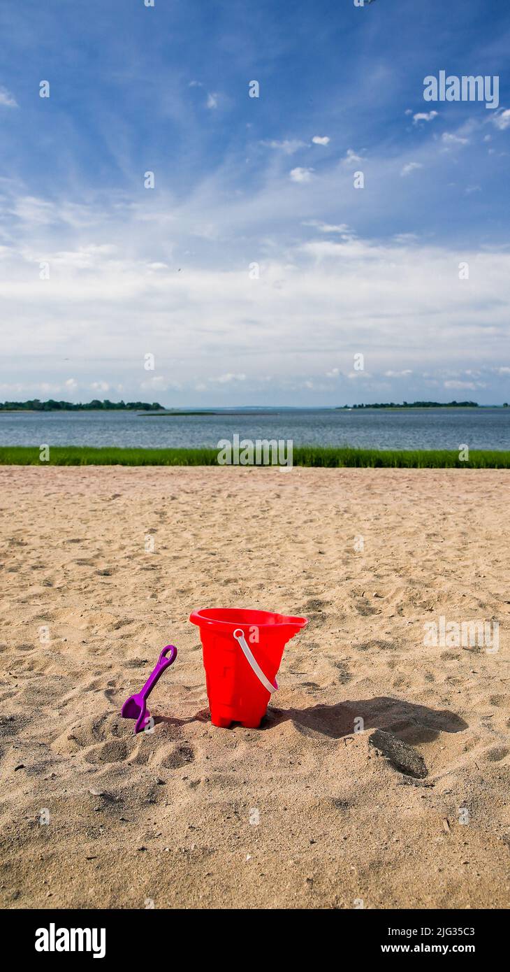 Toy shovel and red bucket on beach in summer day with beautiful sky ...