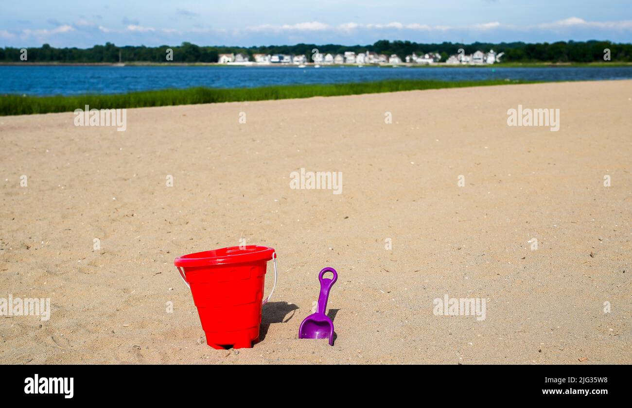 Toy shovel and red bucket on beach in summer day with beautiful sky ...