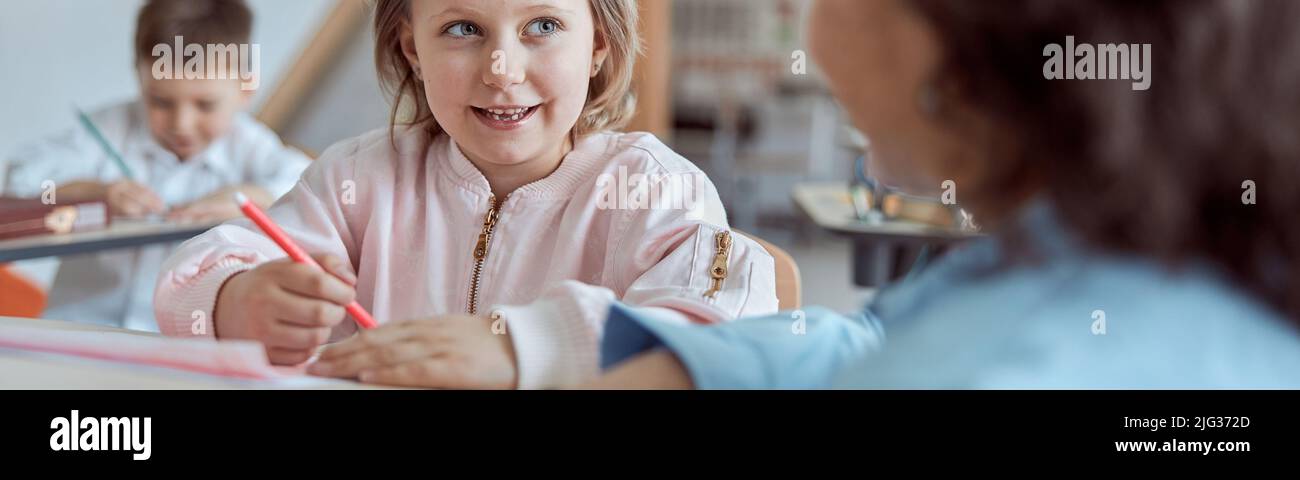 Happy kind teacher is helping kids in elementary school lessons Stock ...