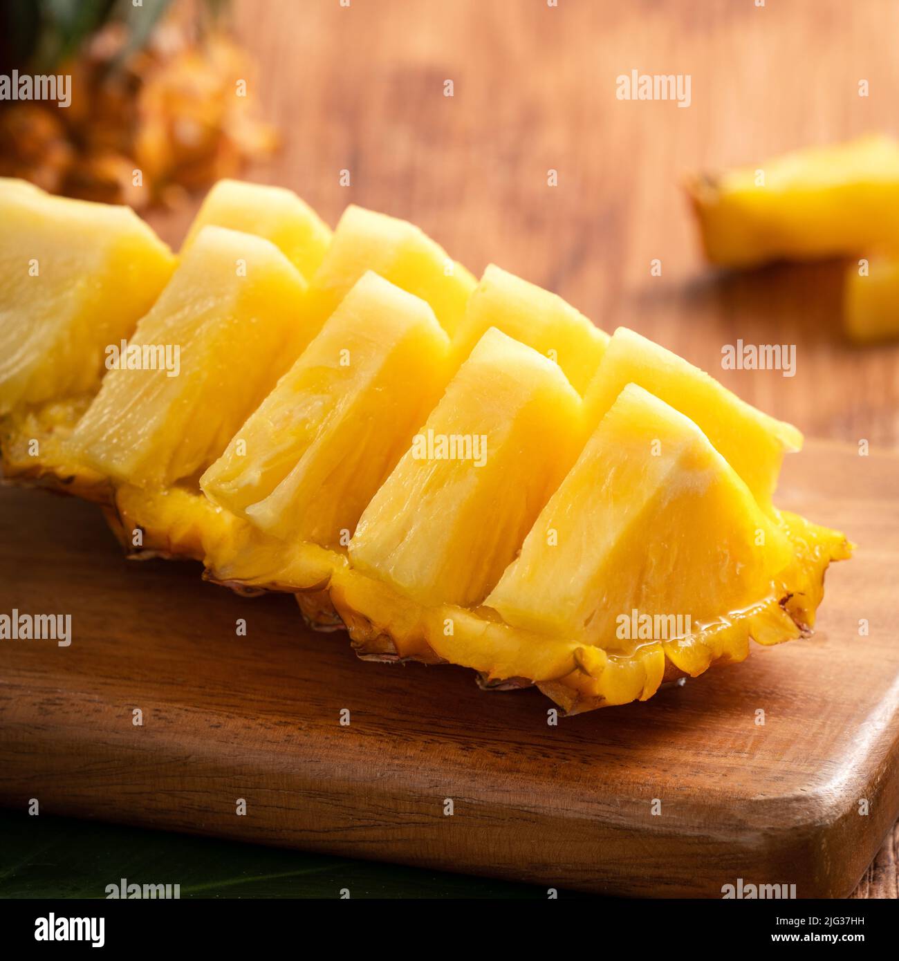 Close up of fresh cut pineapple on a tray over dark wooden table ...