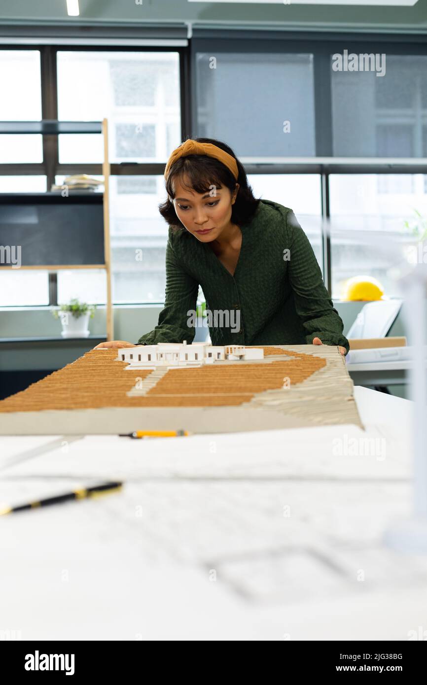 Asian young female architect examining architectural model in office ...