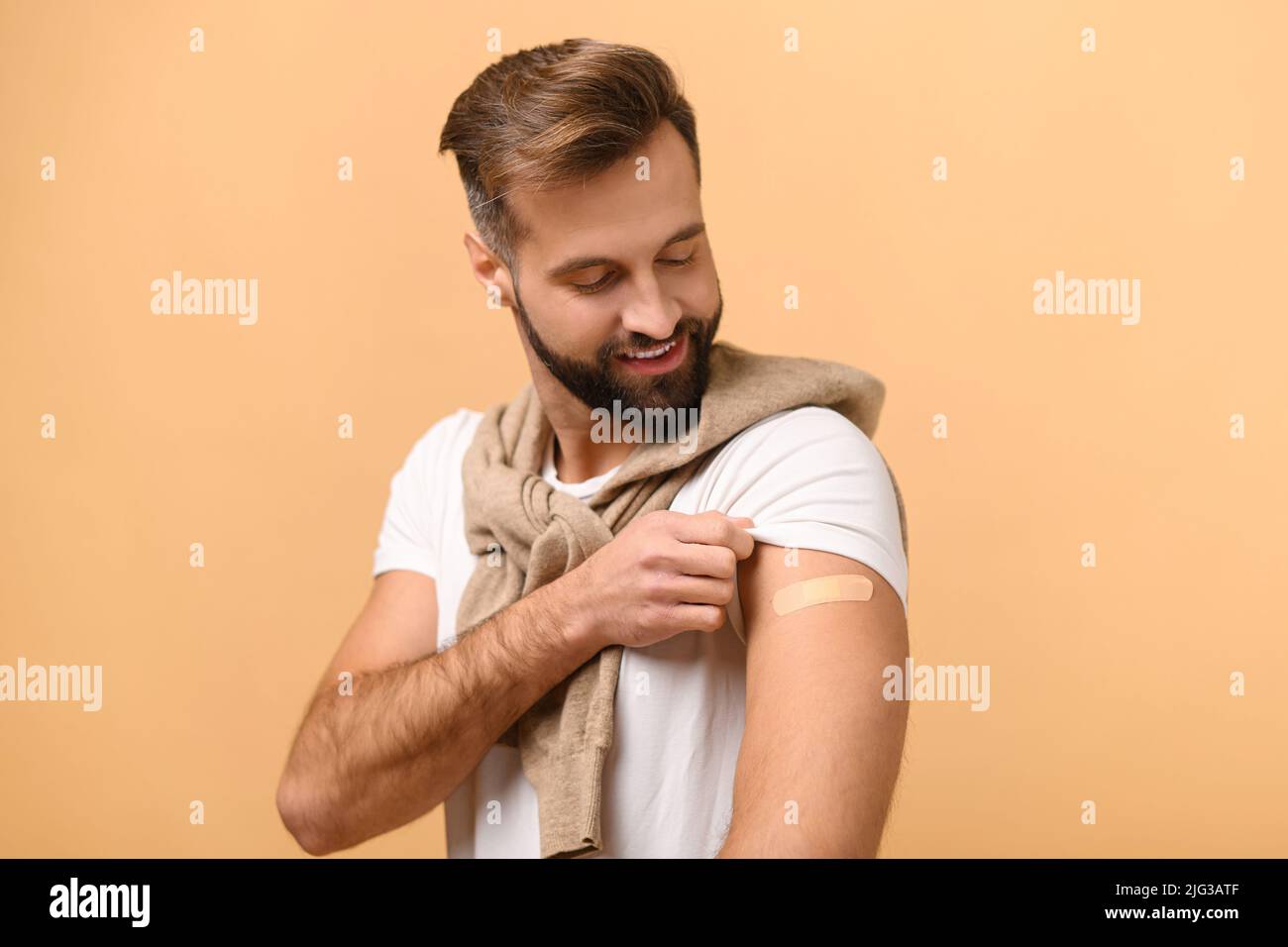 Smiling young guy showing arm with band-aid after vaccine injection ...