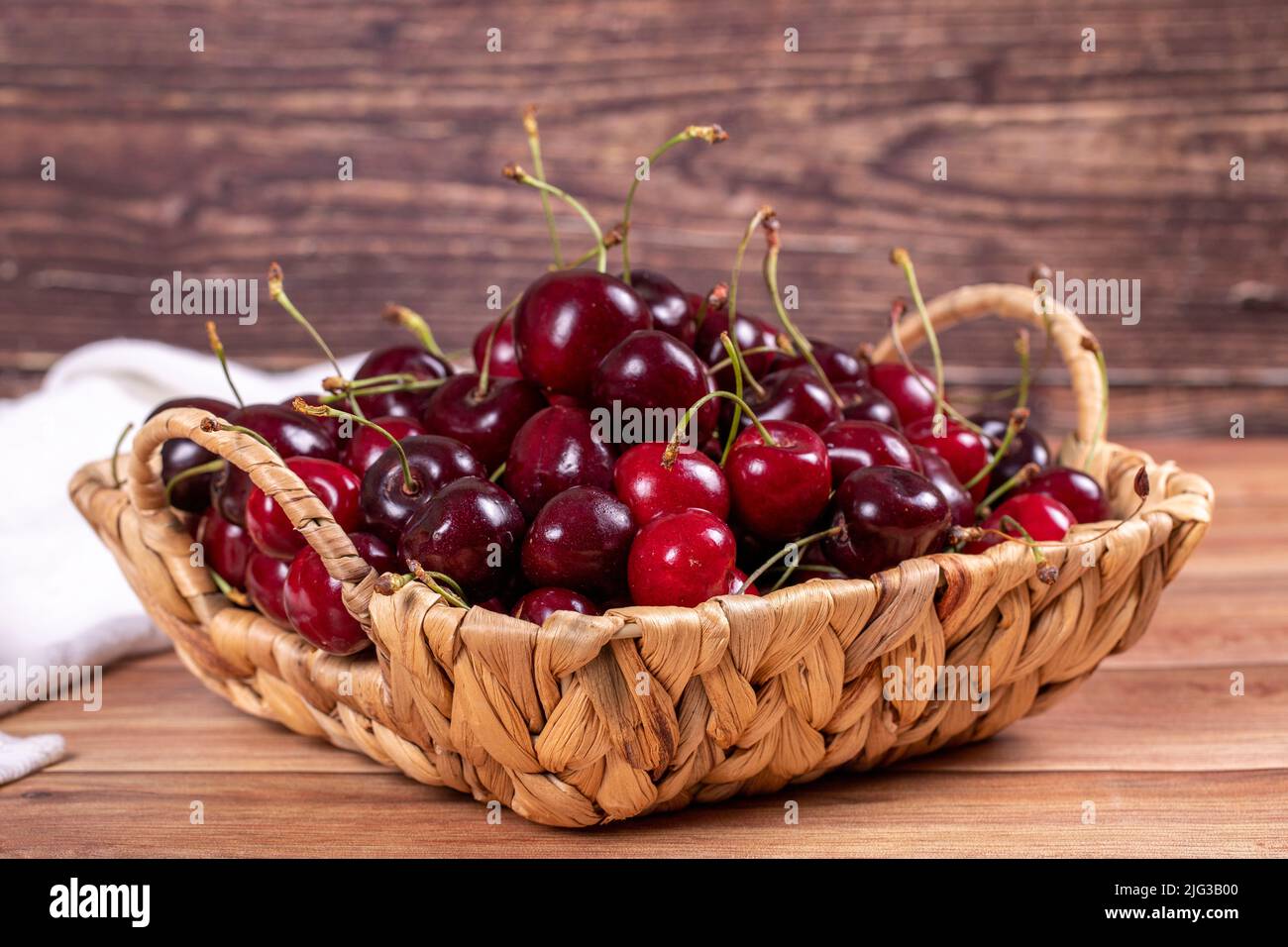 Fresh cherry. Ripe cherries in a basket on wood background. Bulk ...