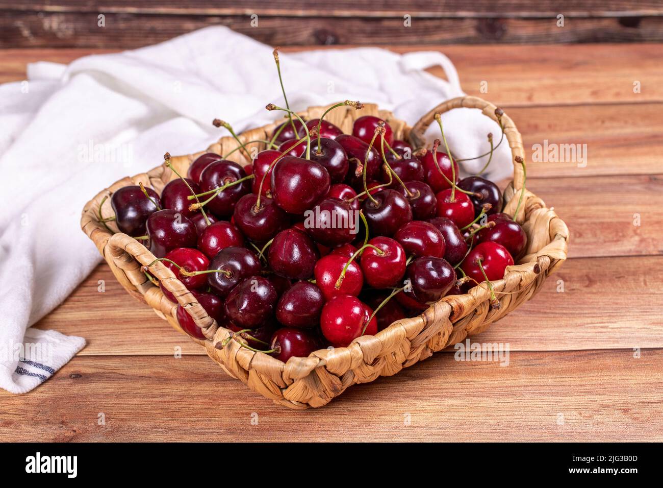 Fresh cherry. Ripe cherries in a basket on wood background. Bulk ...