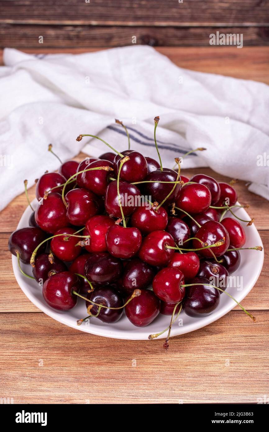 Fresh cherry. Ripe cherries in plate on wood background. Bulk cherries ...