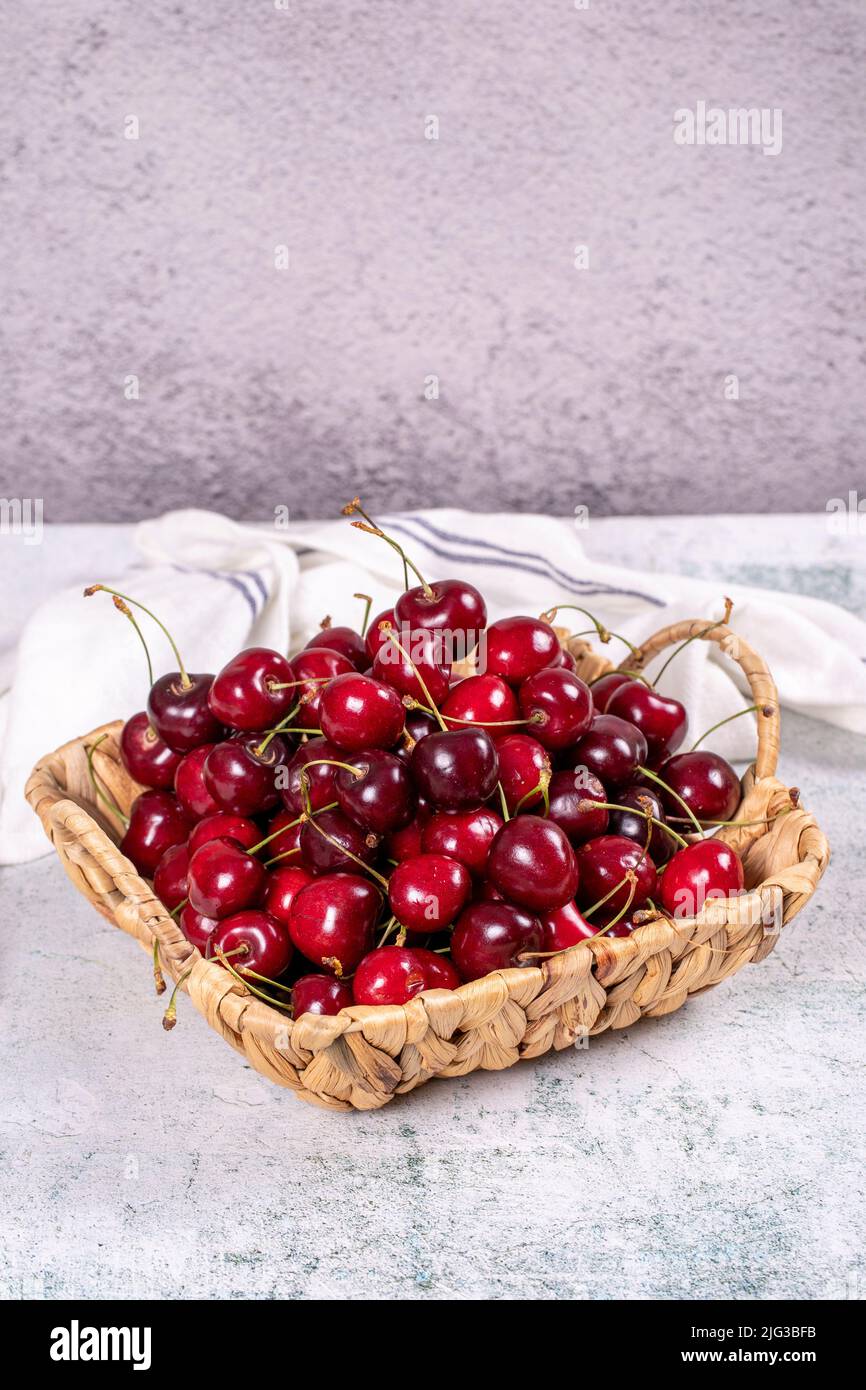 Fresh cherry. Ripe cherries in a basket on a stone background. Bulk ...