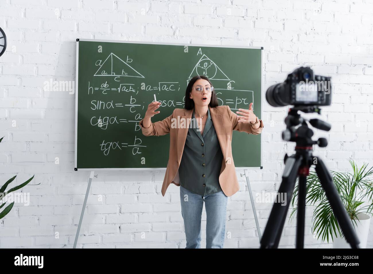 Teacher talking near math formulas on chalkboard and digital camera in ...