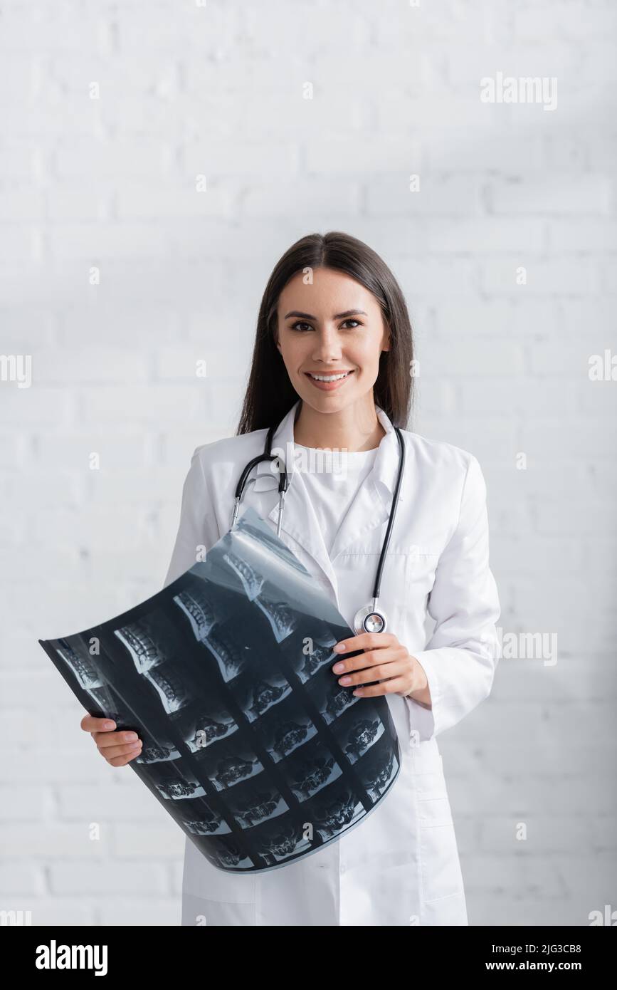 Brunette doctor holding mri scan and looking at camera in clinic Stock ...