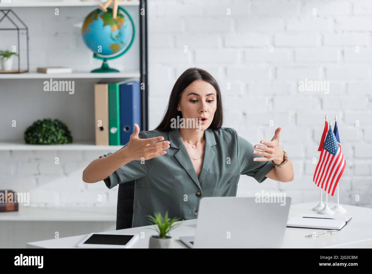 Teacher talking during video call on laptop near digital tablet and ...
