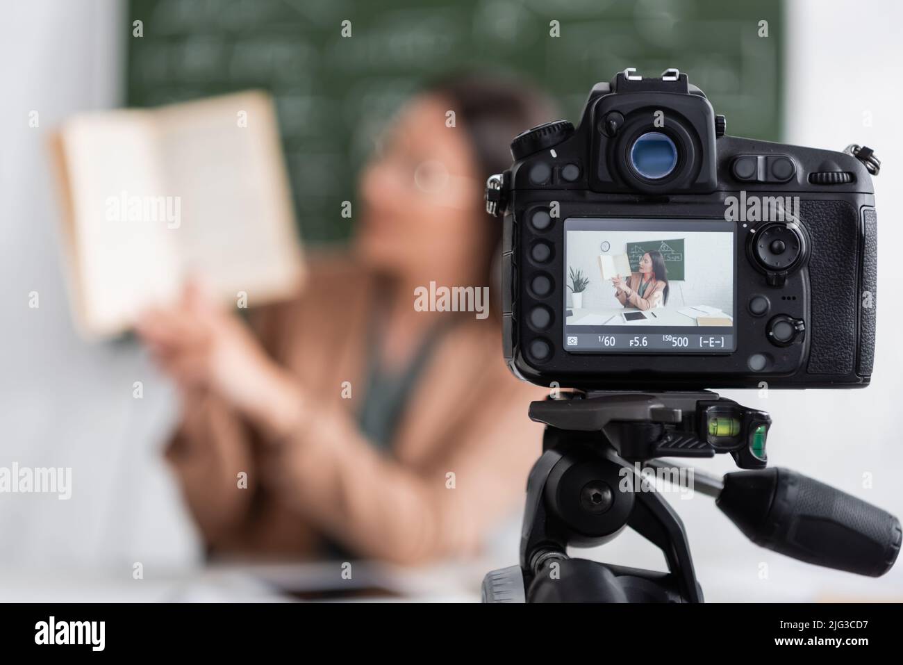 Blurred teacher holding book near digital camera in school Stock Photo ...