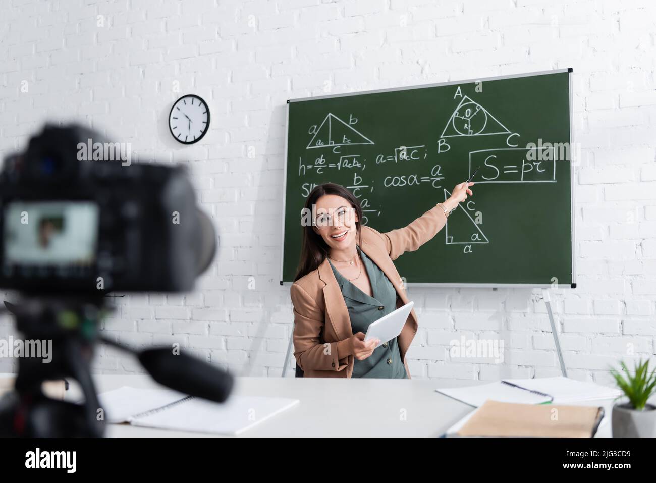 Happy teacher holding digital tablet and pointing at math formulas on ...