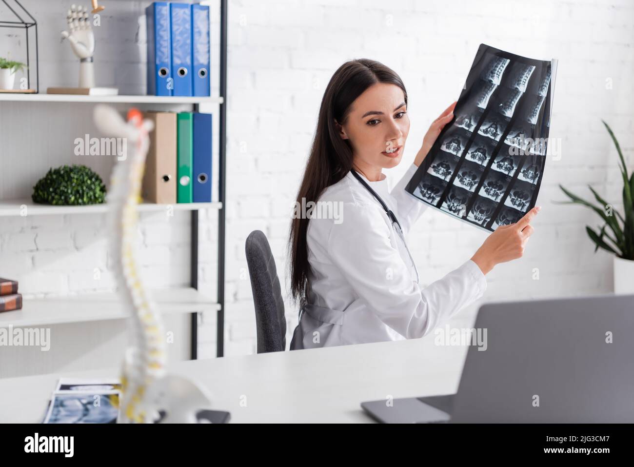 Doctor holding mri scan during video chat on laptop in hospital Stock ...