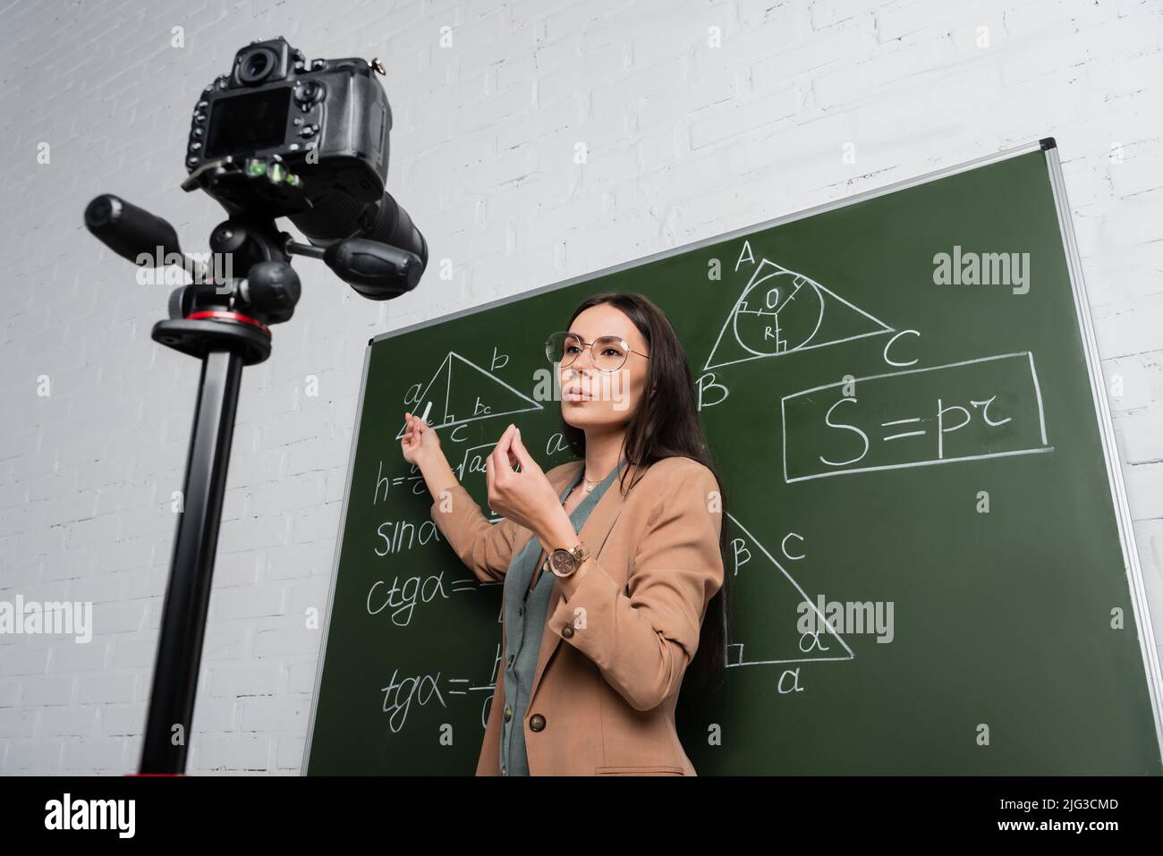 Low angle view of teacher talking near math formulas on chalkboard and ...