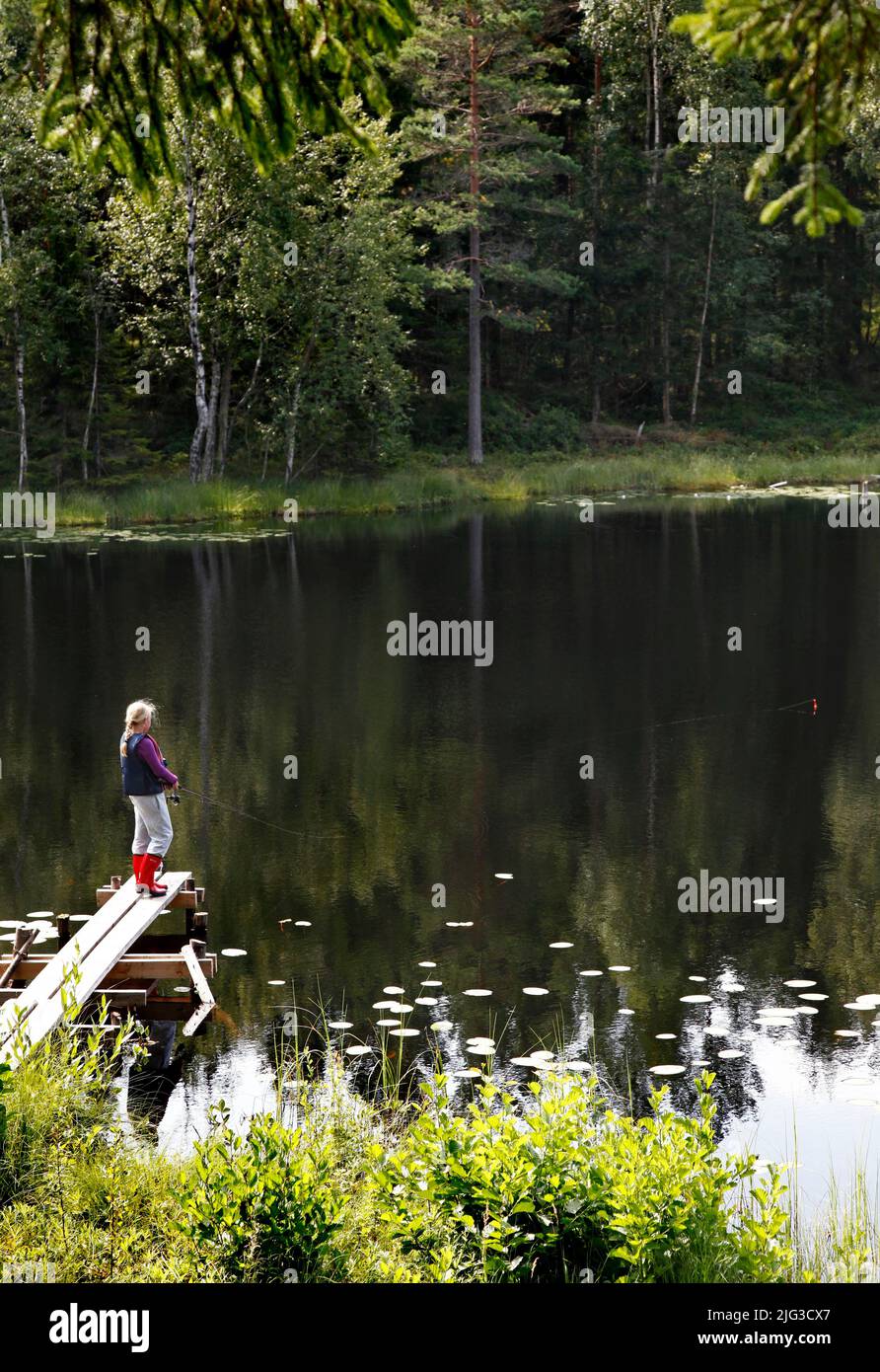 A girl fishing in a forest lake Stock Photo - Alamy