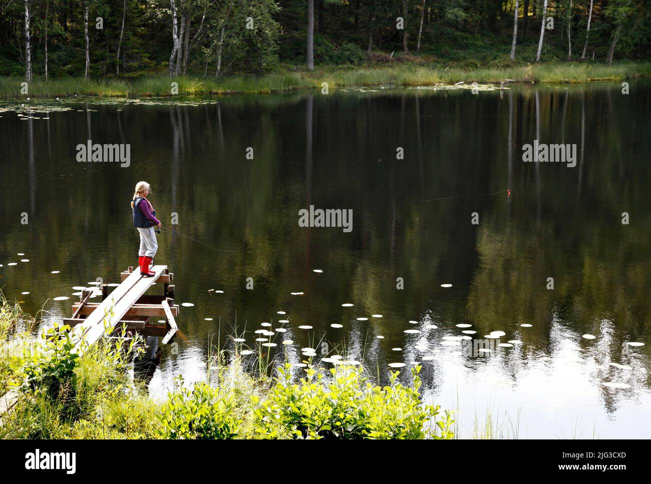 A girl fishing in a forest lake Stock Photo - Alamy