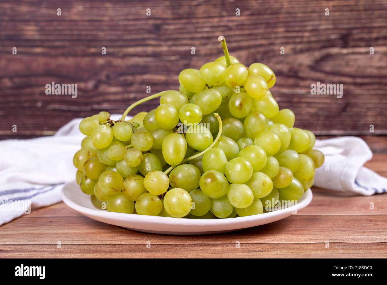 Fresh green grapes. Ripe grapes in plate on wood background. Bulk ...