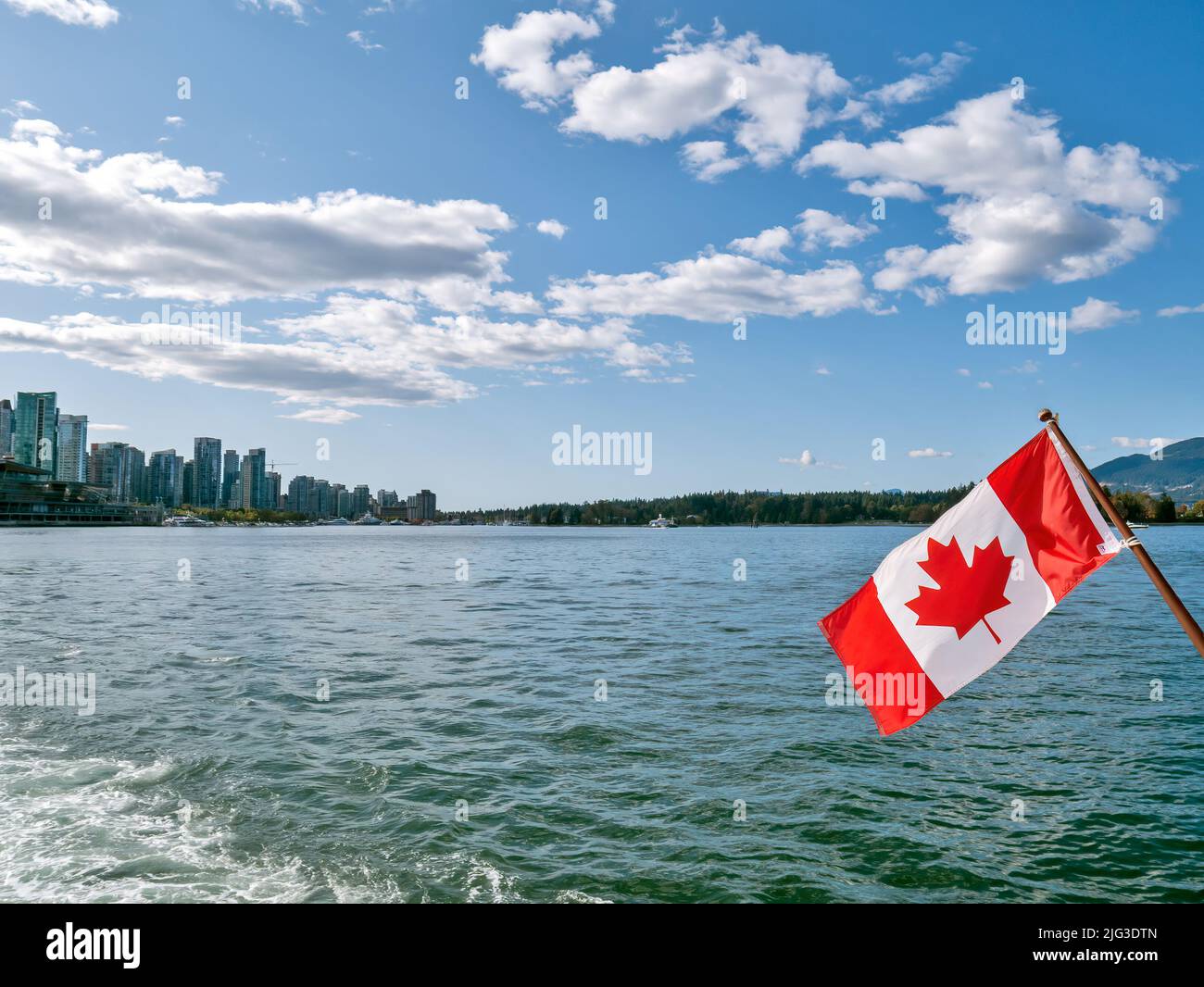 Canadian flag on blue sky and water background in Vancouver harbor ...