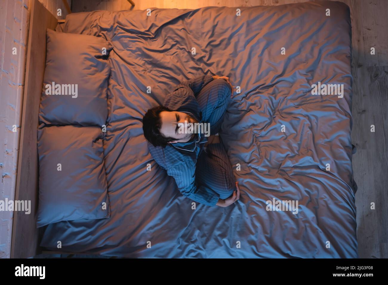 Overhead view of man with sleep disorder sitting with closed eyes on ...