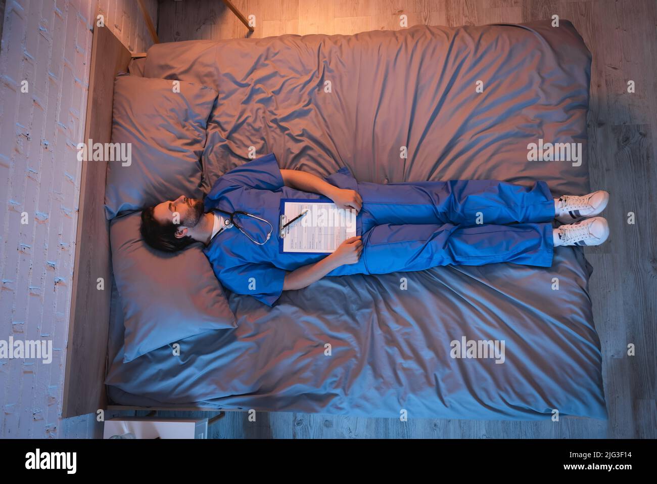 Side view of somnambulist in doctor uniform holding clipboard while ...