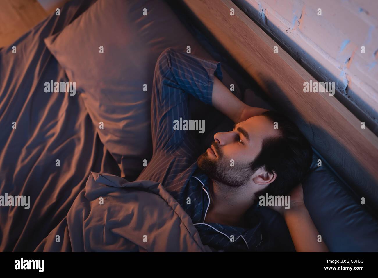 Side view of man with sleep disorder lying on bed at home Stock Photo ...