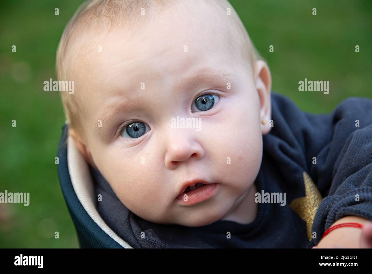 Portrait of a beautiful baby girl. The baby looks into the camera with ...