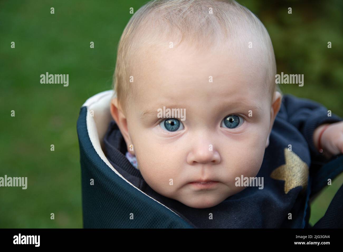 Portrait of a beautiful baby girl. The baby looks into the camera with ...