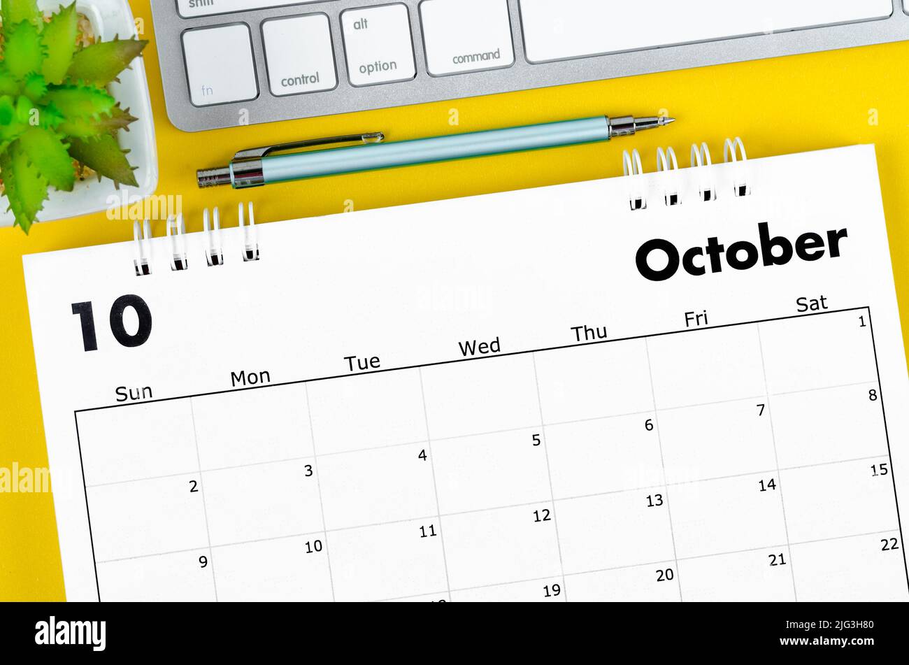 The October 2022 desk calendar with pen and keyboard computer on yellow ...