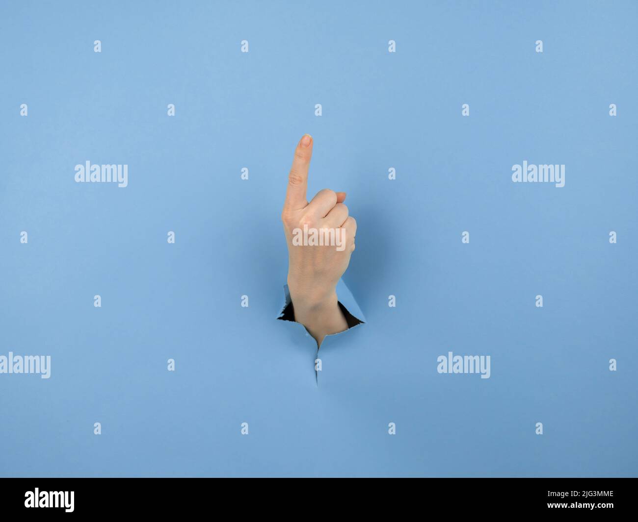 A woman's hand sticking out of a hole from a blue background shows her ...