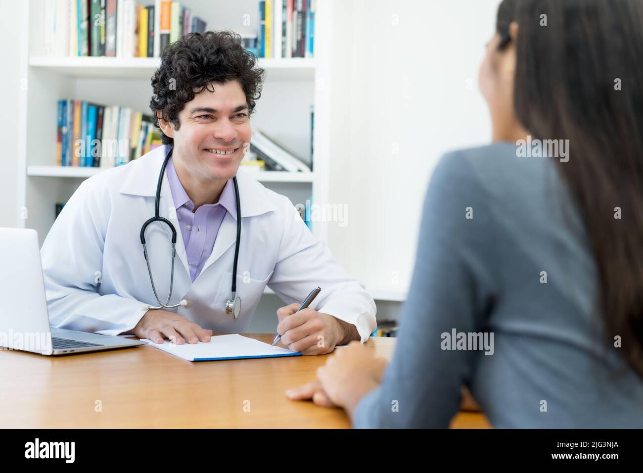 Laughing doctor talking with female patient about good news at office ...