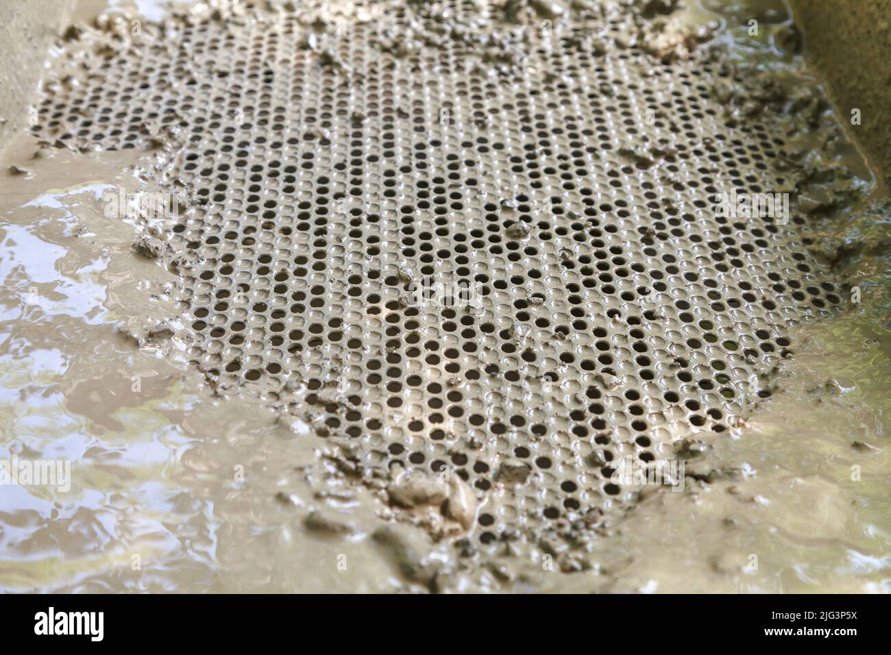 Metal sieve with round holes to clean dirty water from small stones ...